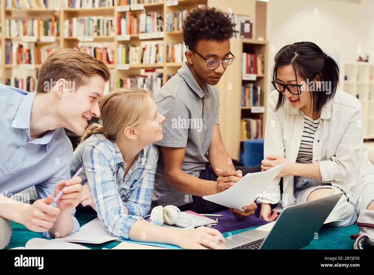 Group of positive young multi-ethnic students studiying in modern ...