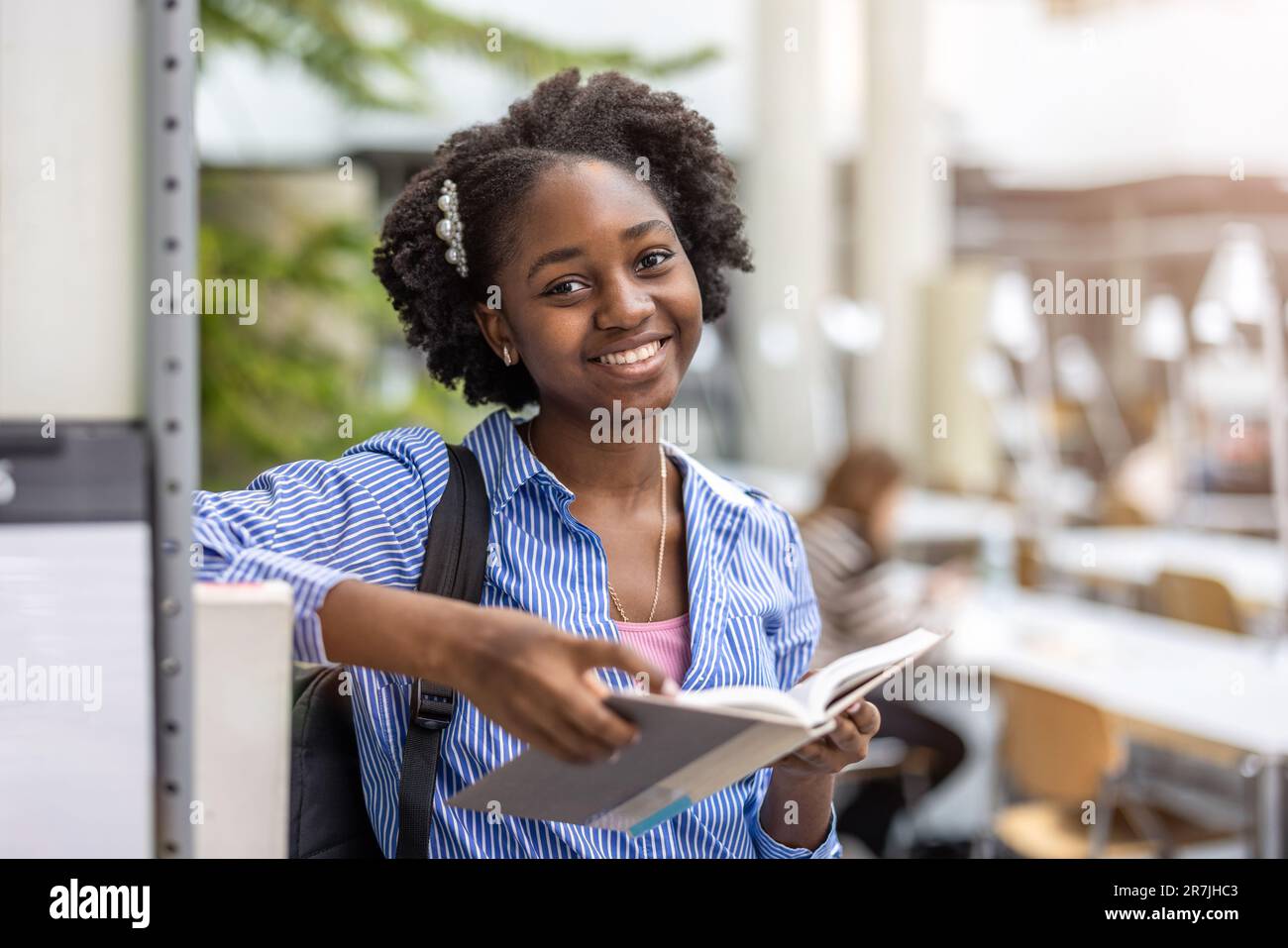 Black female student reading a book in a library Stock Photo - Alamy