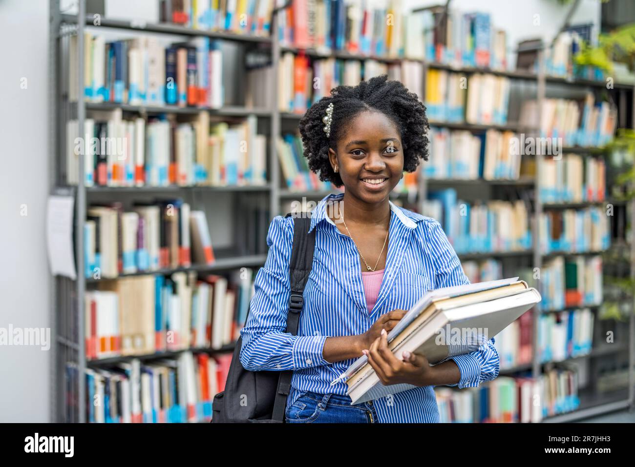 Portrait of black female student standing in a library Stock Photo - Alamy