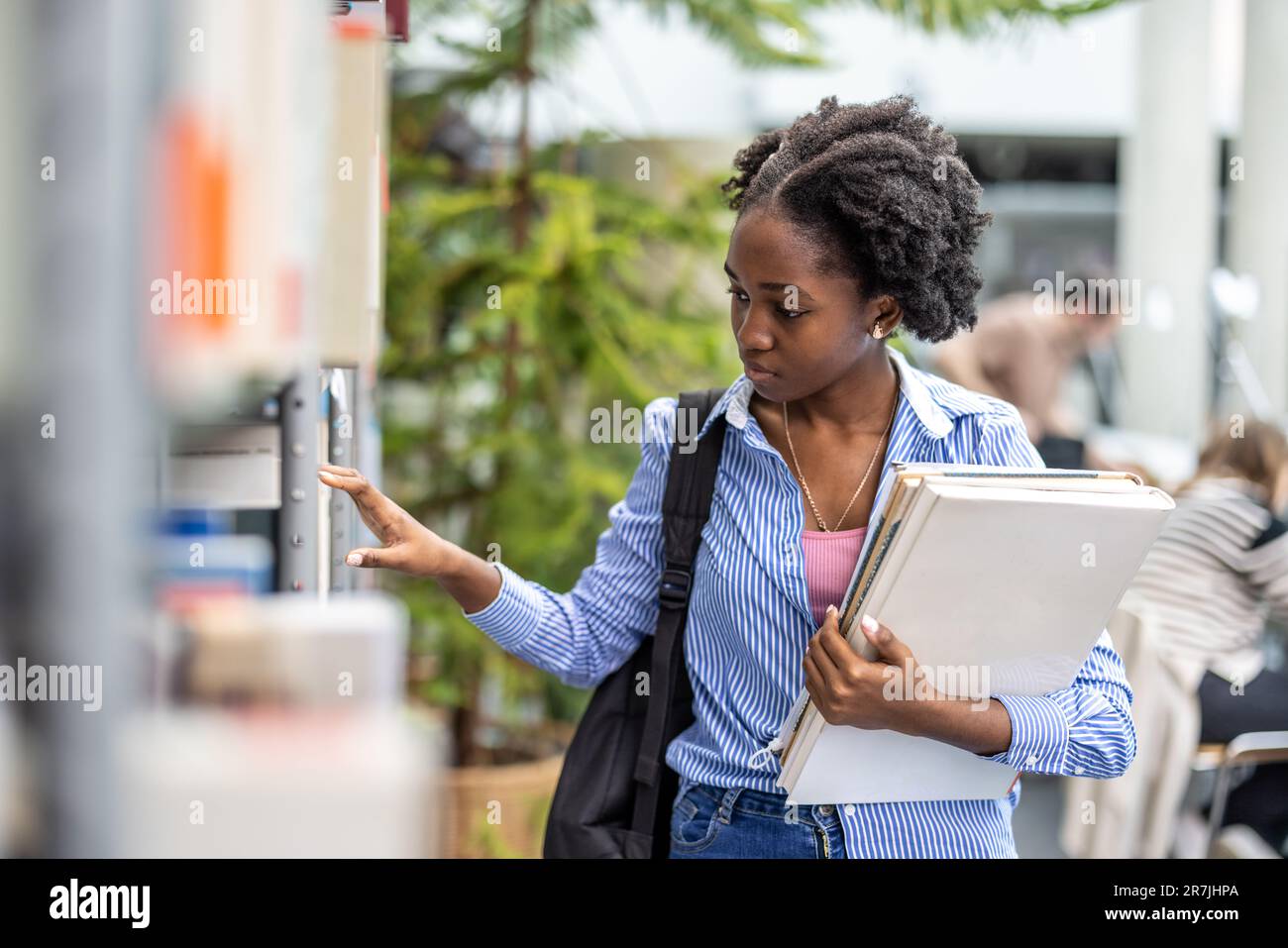 Portrait of black female student standing in a library Stock Photo - Alamy