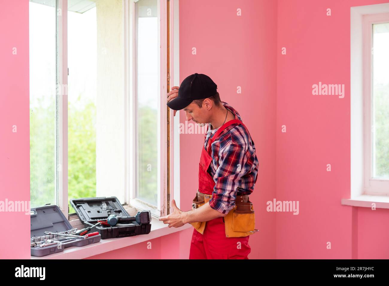 handyman adjusting white pvc plastic window indoors. worker using ...