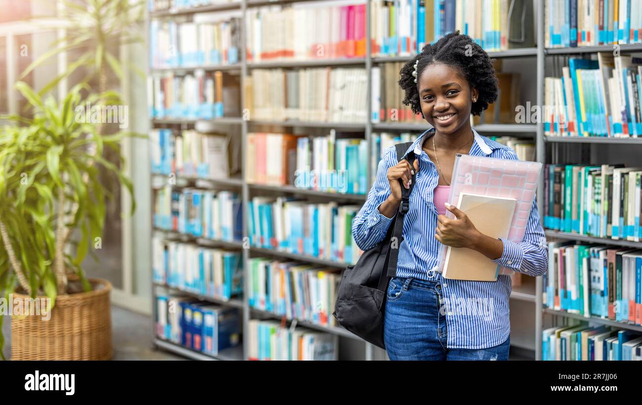 Portrait of black female student standing in a library Stock Photo - Alamy