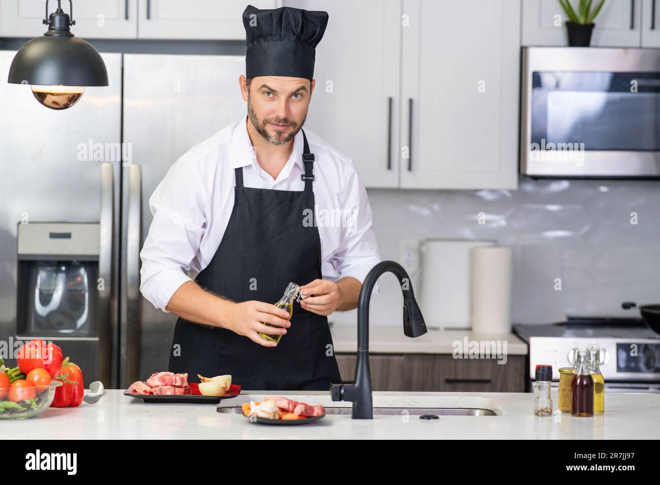 Attractive man cooking in modern kitchen. Handsome man cooking at home ...