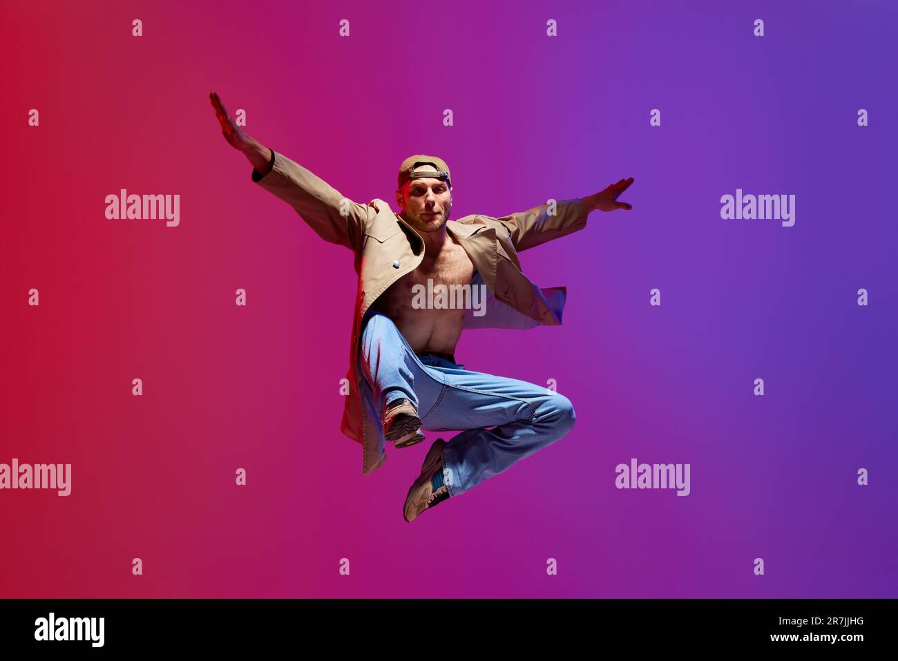 Active, artistic young man in casual clothes dancing breakdance ...