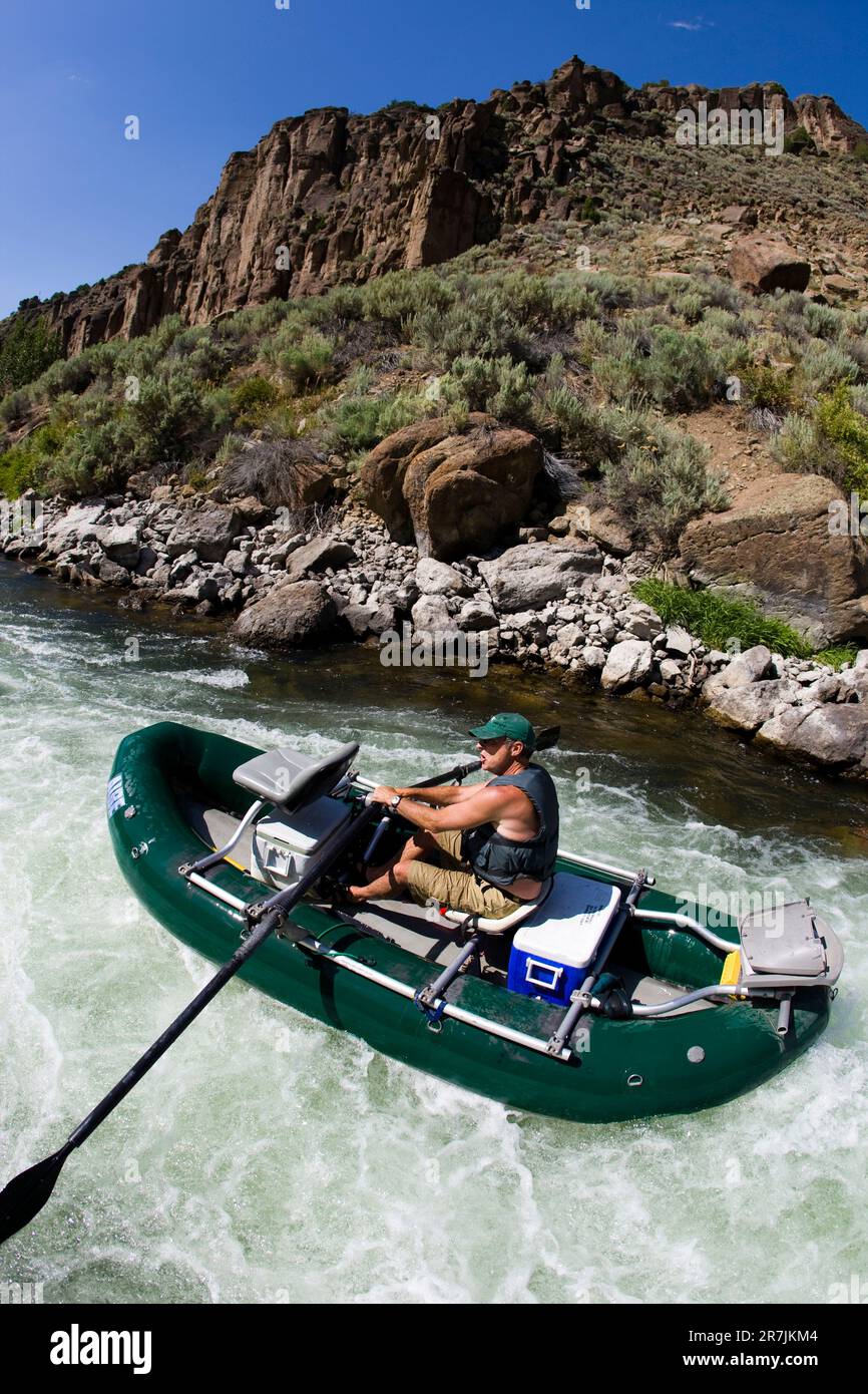 Male negotiates the Teton River on a nice summer day. Basalt pinnacles ...