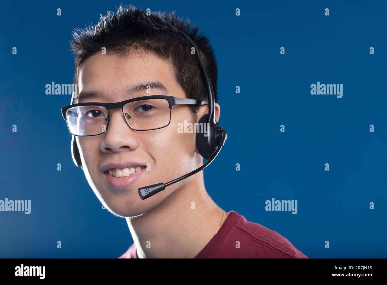 A young smiling Asian adult wears a typical gamer or call center ...