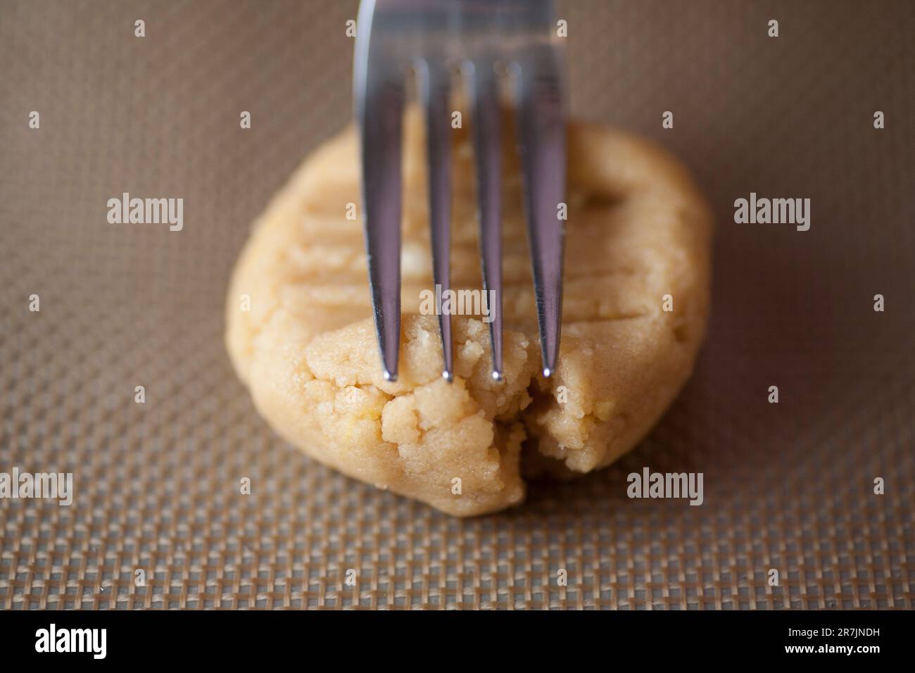 A fork is used to shape an organic peanut butter cookie in a kitchen in ...