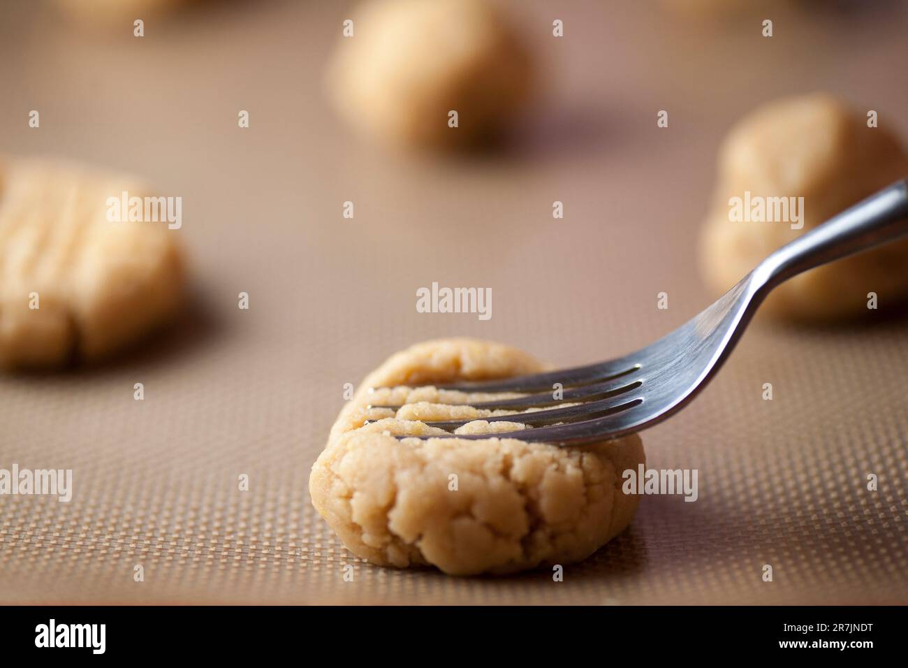 A fork is used to shape an organic peanut butter cookie in a kitchen in ...