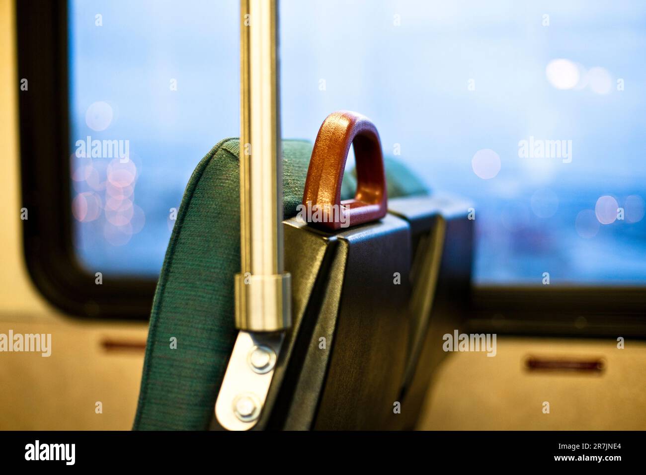 A bus seat on a city bus at dusk sits empty as lights stream by in ...