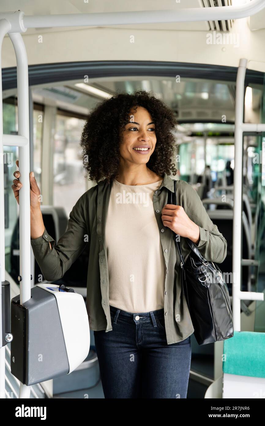 Young relaxed woman standing while commuting in public transportation ...