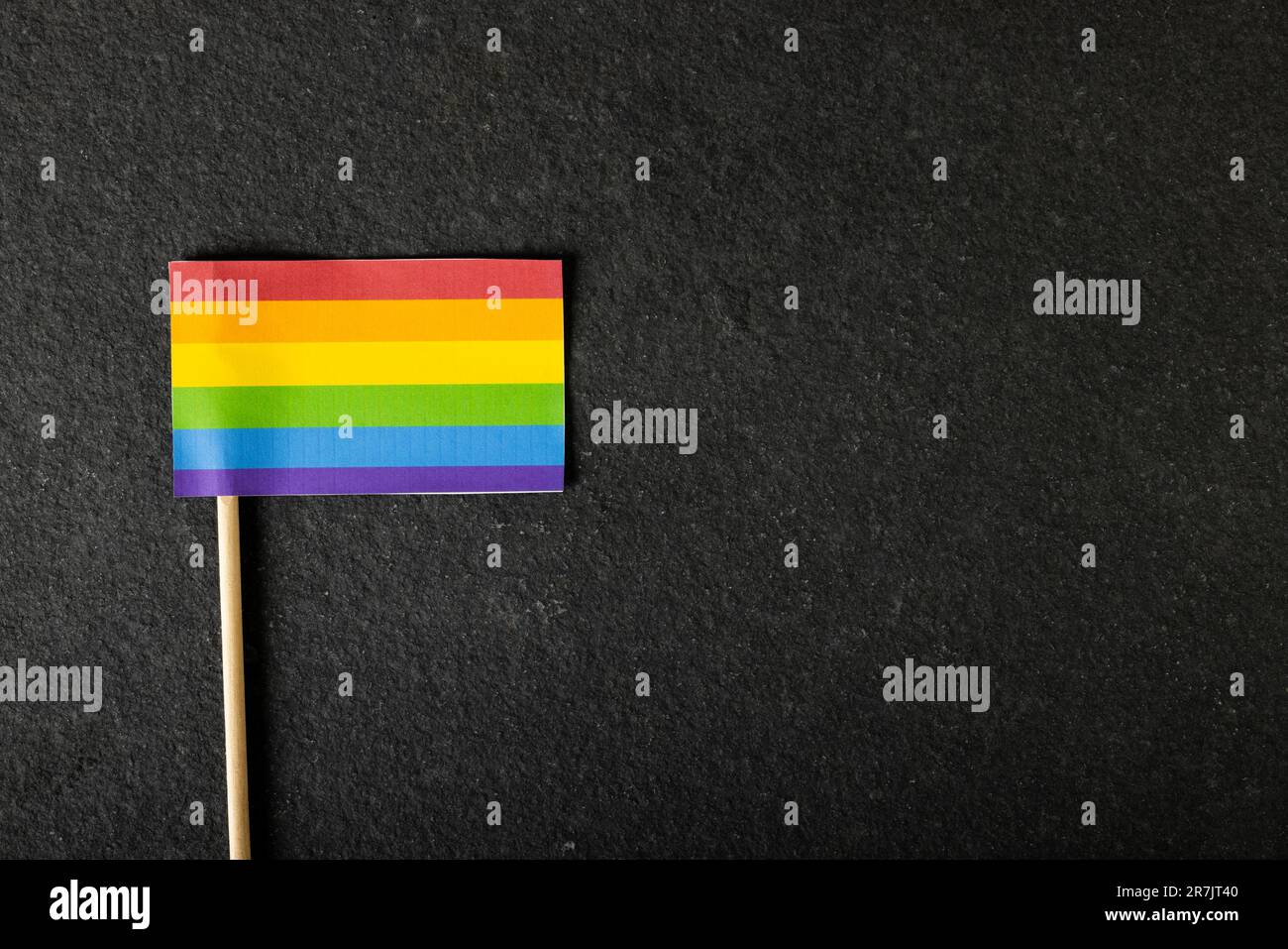 Overhead view of rainbow flag isolated against black table, copy space ...