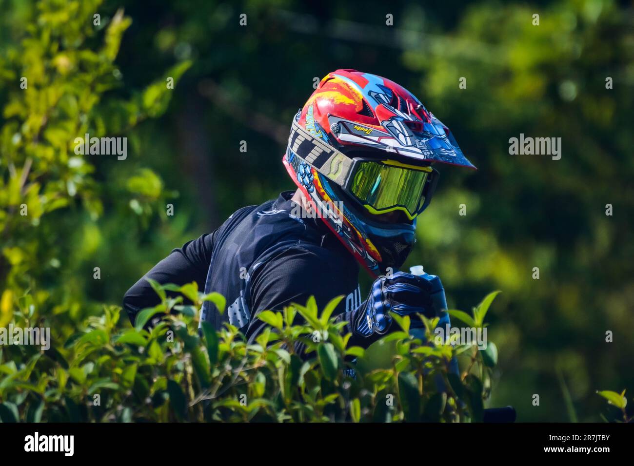 A motorcyclist with goggles and a colorful helmet looking back from ...