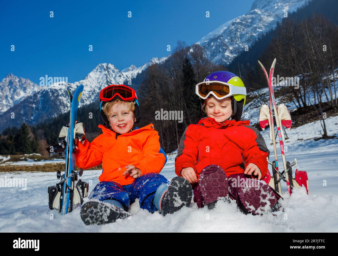 Two kids enjoy first ski alpine vacation, sitting in snow Stock Photo ...