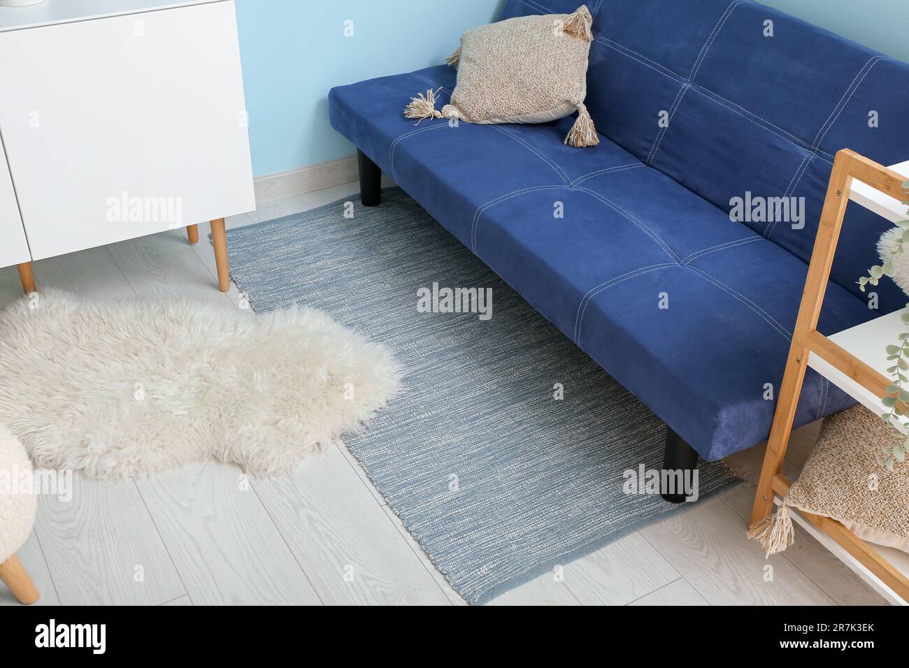 Stylish interior of living room with drawers, sofa, shelving unit and ...