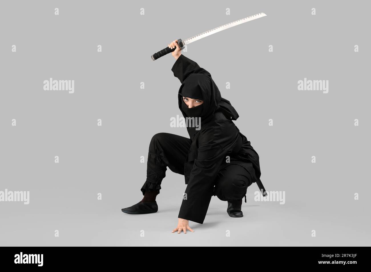 Female ninja with sword on grey background Stock Photo - Alamy