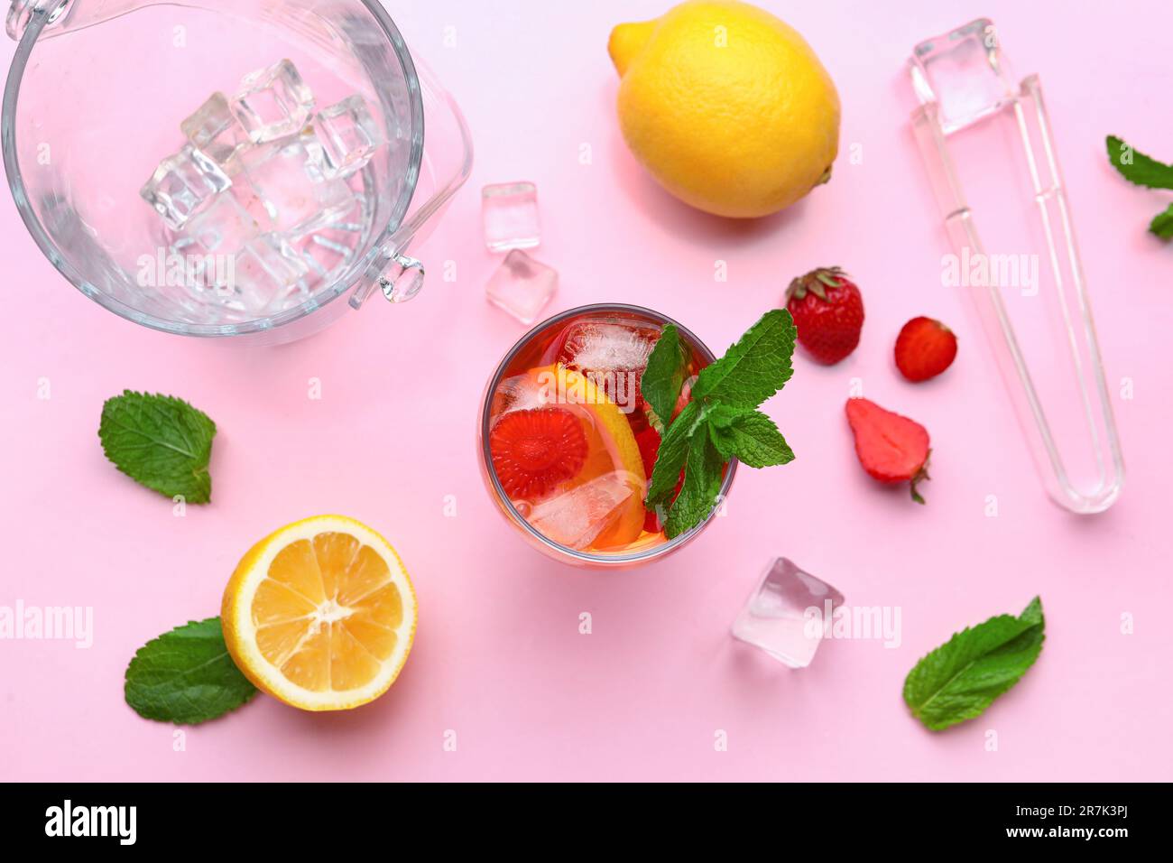 Glass of infused water with strawberry and lemon on pink background ...
