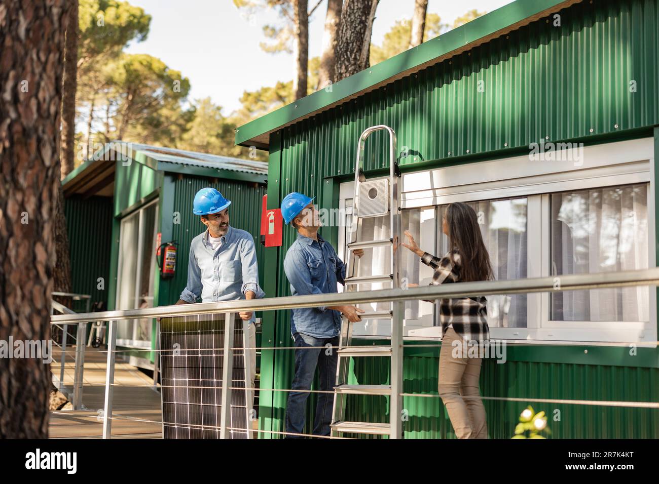 Photovoltaic technicians mounting solar panel on sustainable house with ...