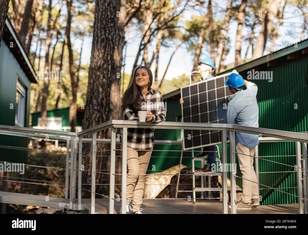 Photovoltaic technicians mounting solar panel on sustainable house with ...