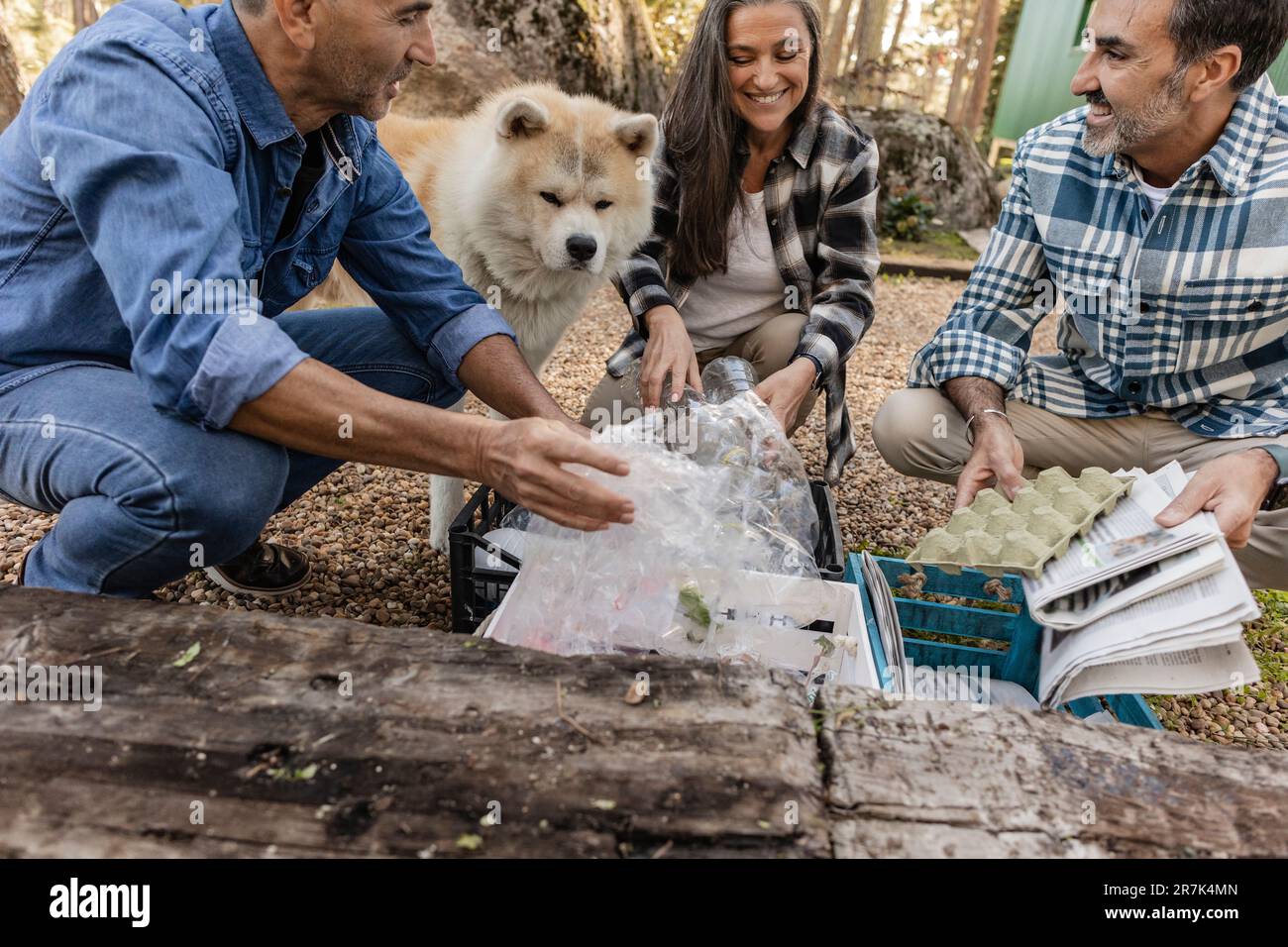 People crouching in garden separating waste into different crates Stock ...