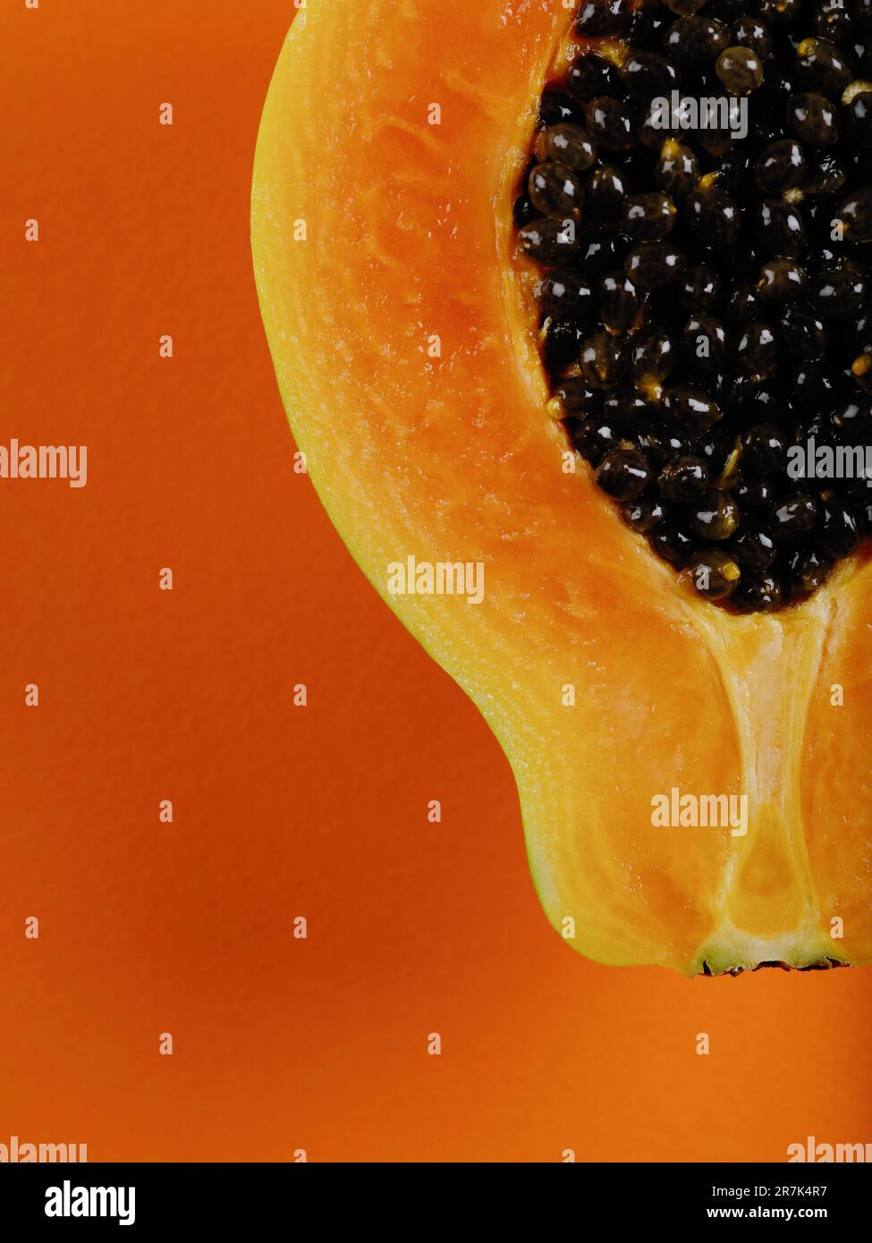 A vertical closeup of a ripe papaya on an orange background Stock Photo ...