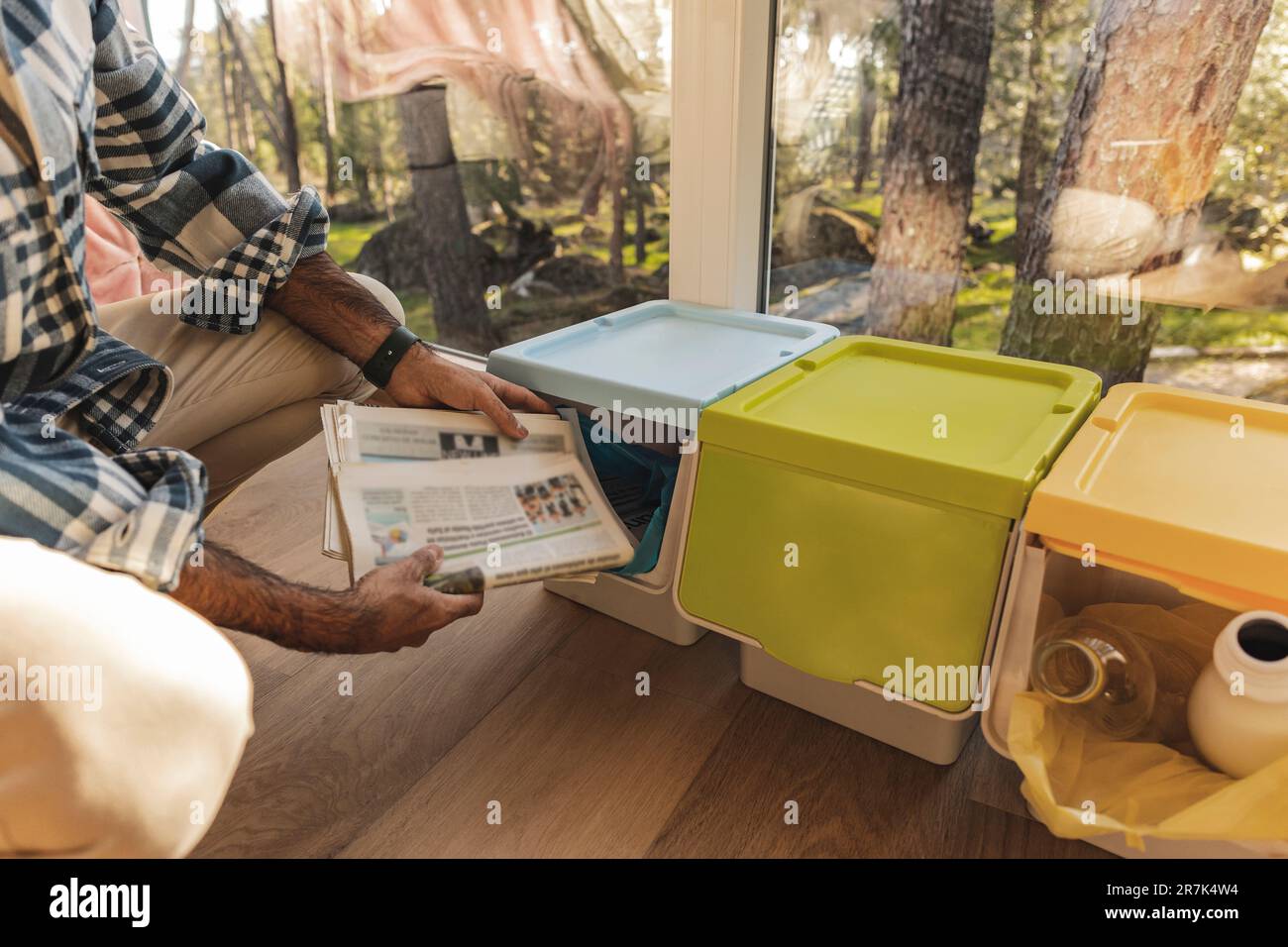 Man putting waste paper into waste separation bin Stock Photo - Alamy