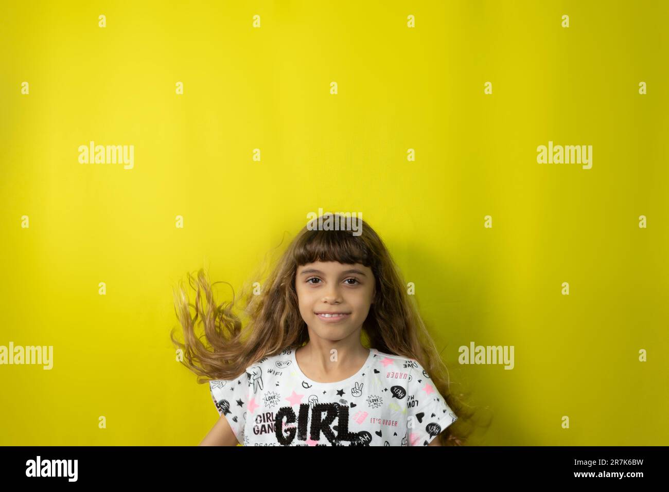 Beautiful girl throwing her long hair up. Isolated on yellow background ...
