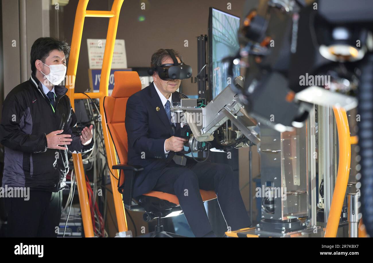 Japanese Minister Tetsuo Saito works a human-shaped heavy machine robot ...