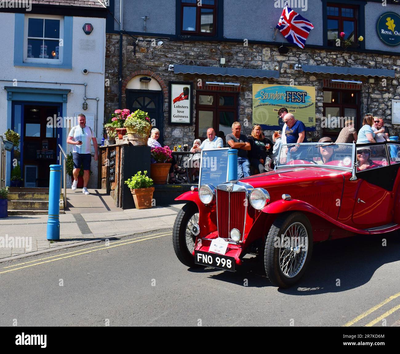 Classic MG sports car passing The Harbwr Bar and Kitchen pub on a local ...