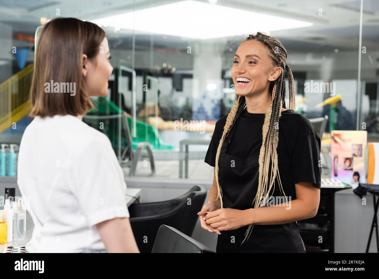 happy beauty worker welcoming female client, cheerful hair stylist with ...