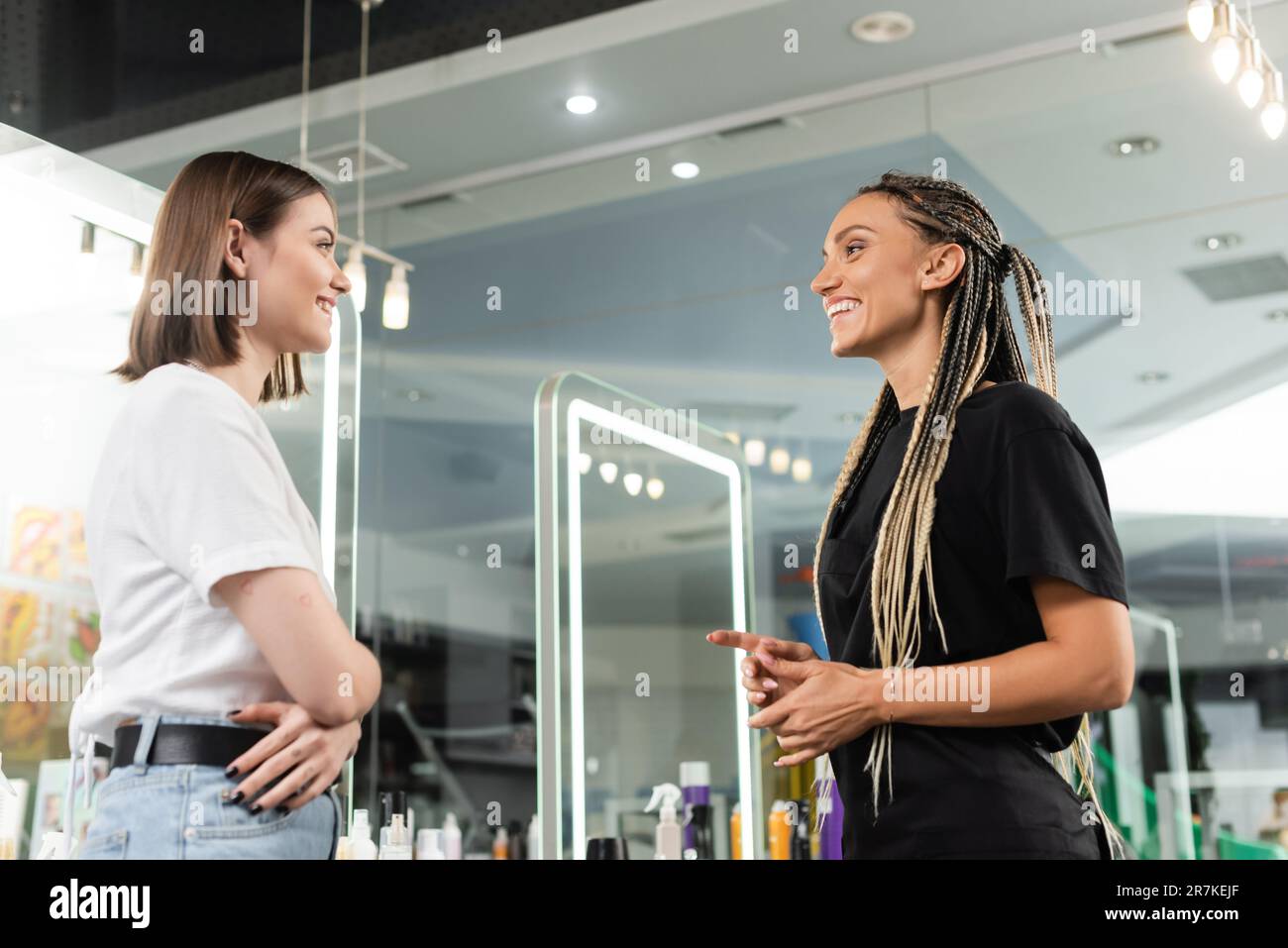 happy beauty worker welcoming female client, cheerful hair stylist with ...