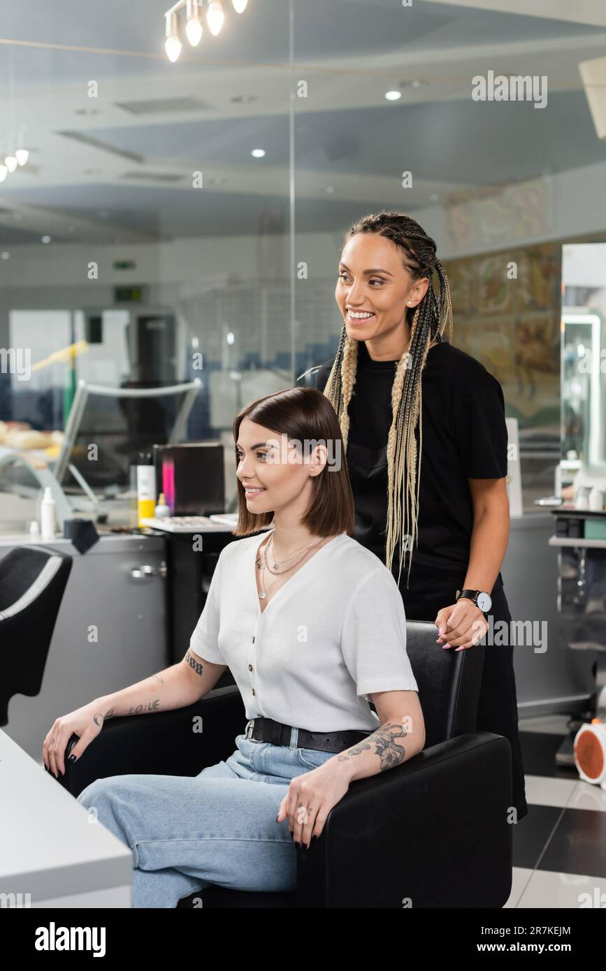 happy hairdresser and female client in beauty salon, cheerful beauty ...