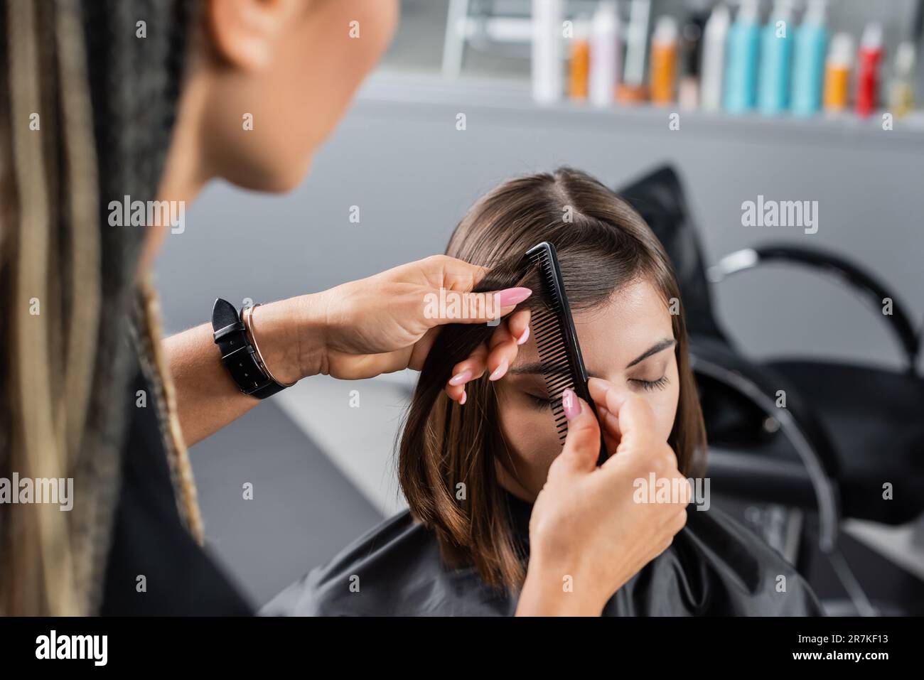 beauty profession, hairdo, hairdresser with braids brushing short ...