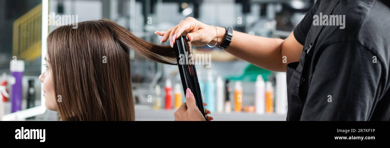hair ironing, professional hairdresser with hair straightener styling ...