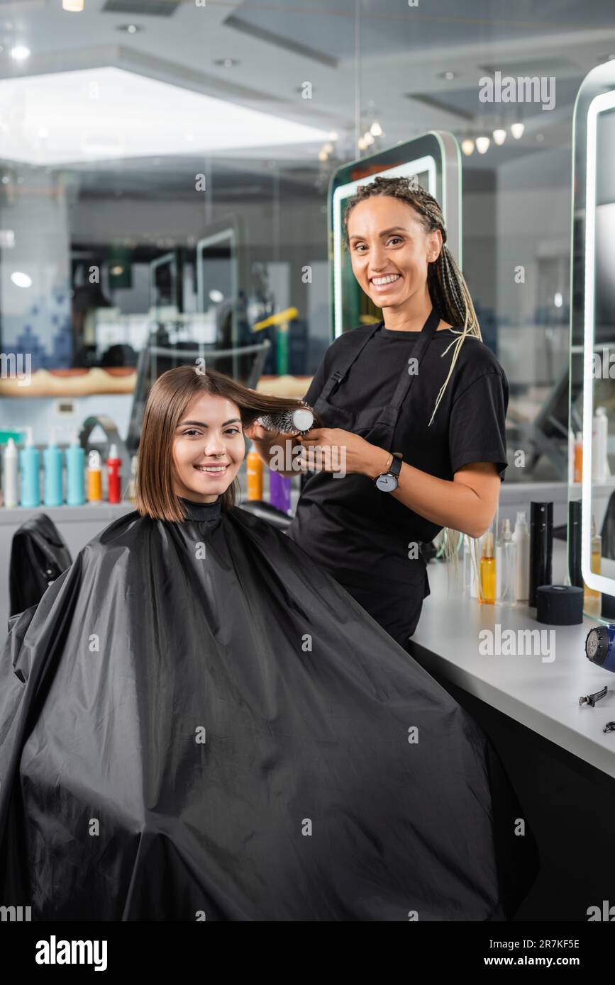 salon services, hairdresser with round brush styling hair of female ...