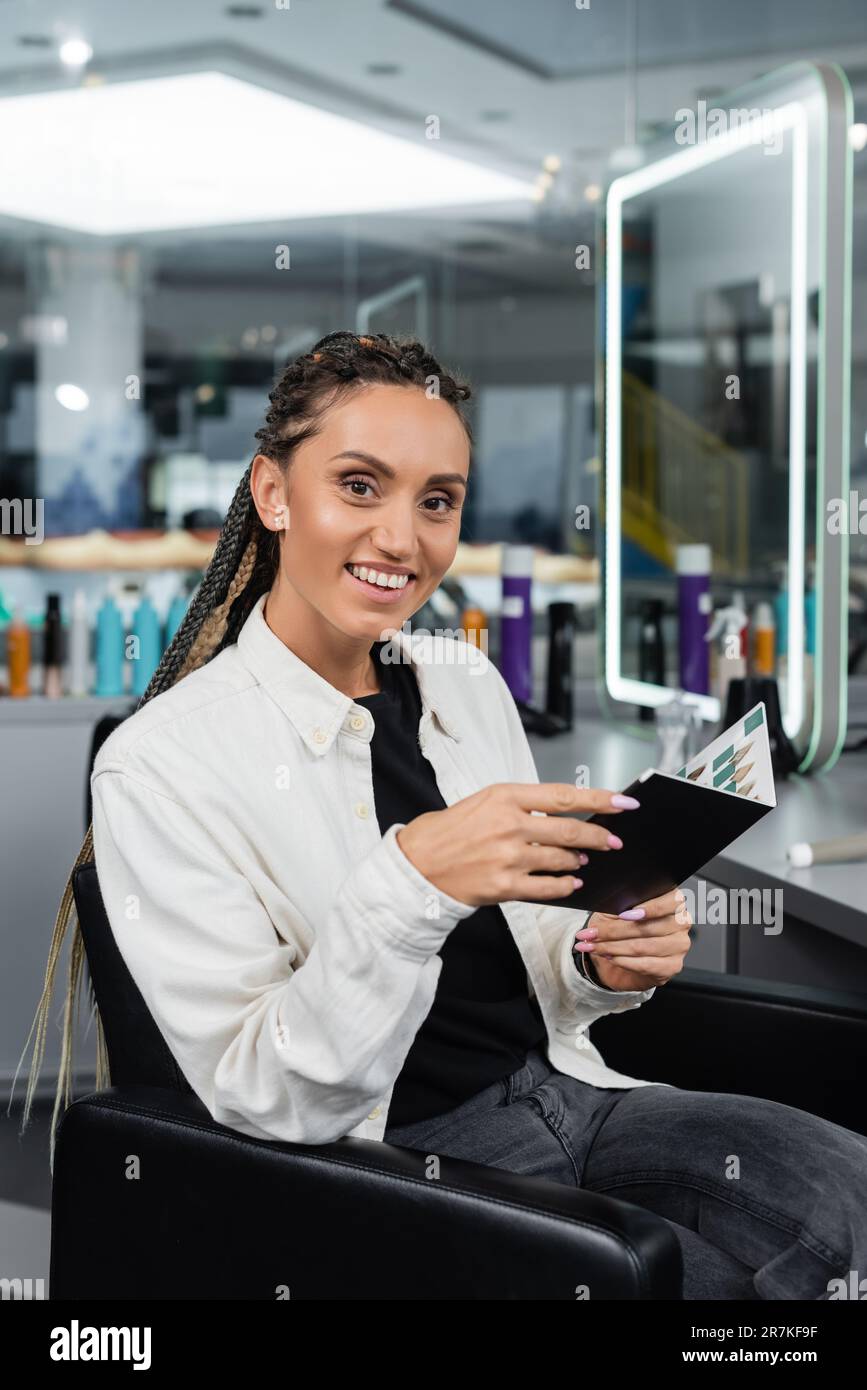 salon customer, woman with braids holding hair color palette in beauty ...