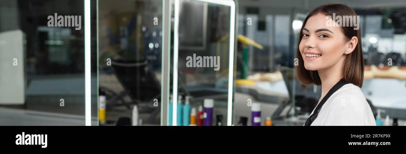 hair salon, happy beauty worker in apron holding hair color palette in ...