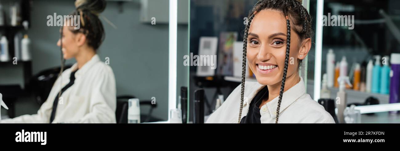 happy client in beauty salon, cheerful woman with hair bun looking at ...