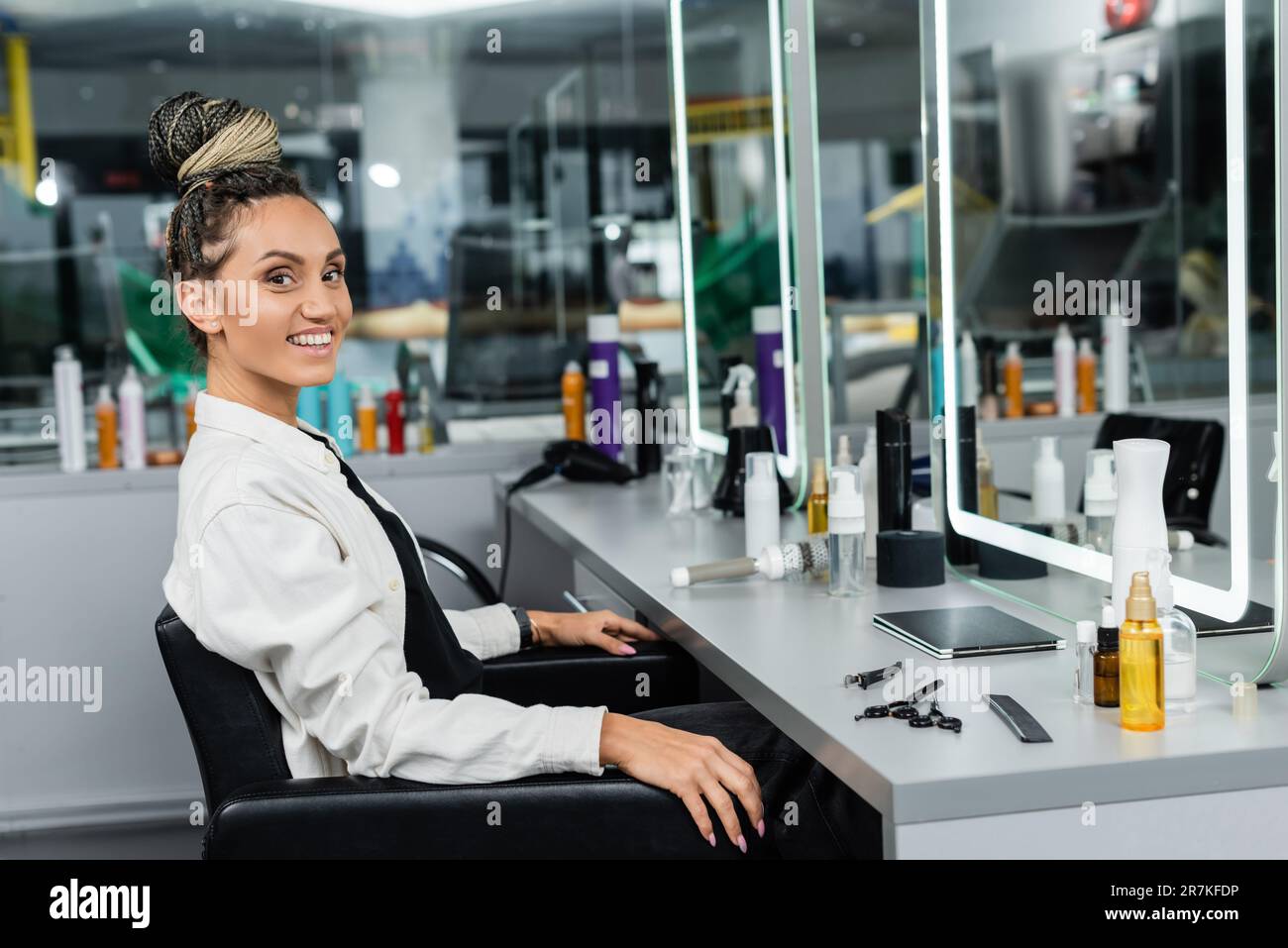 happy client in beauty salon, cheerful woman with hair bun looking at ...