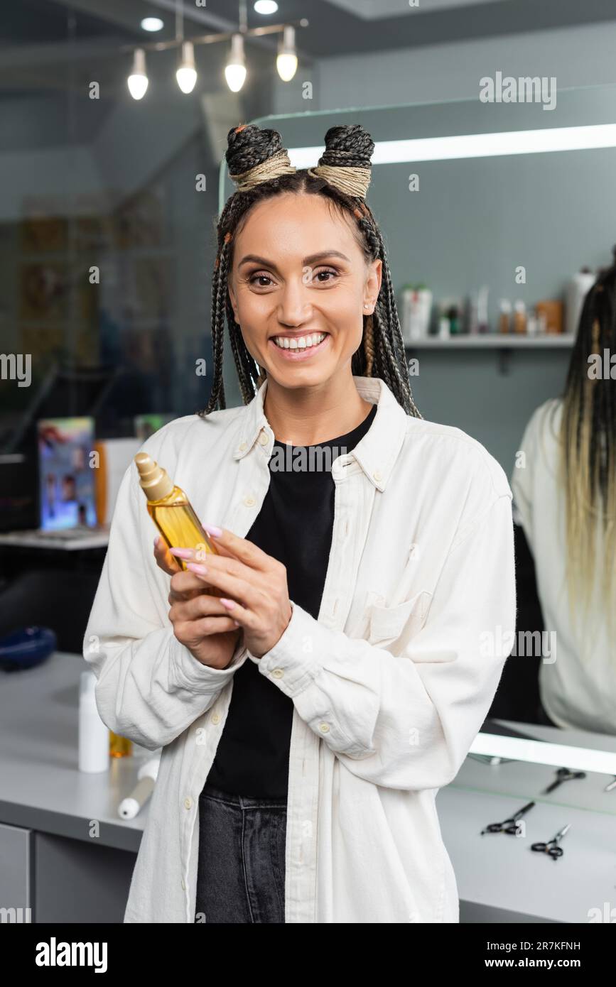 happy woman in beauty salon, joyful client with braids looking at ...