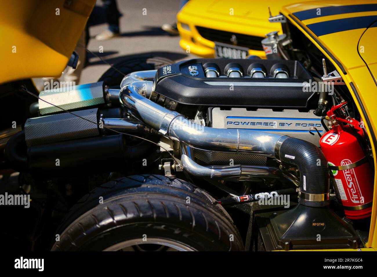 A close-up image of a yellow car featuring a large engine in the trunk ...