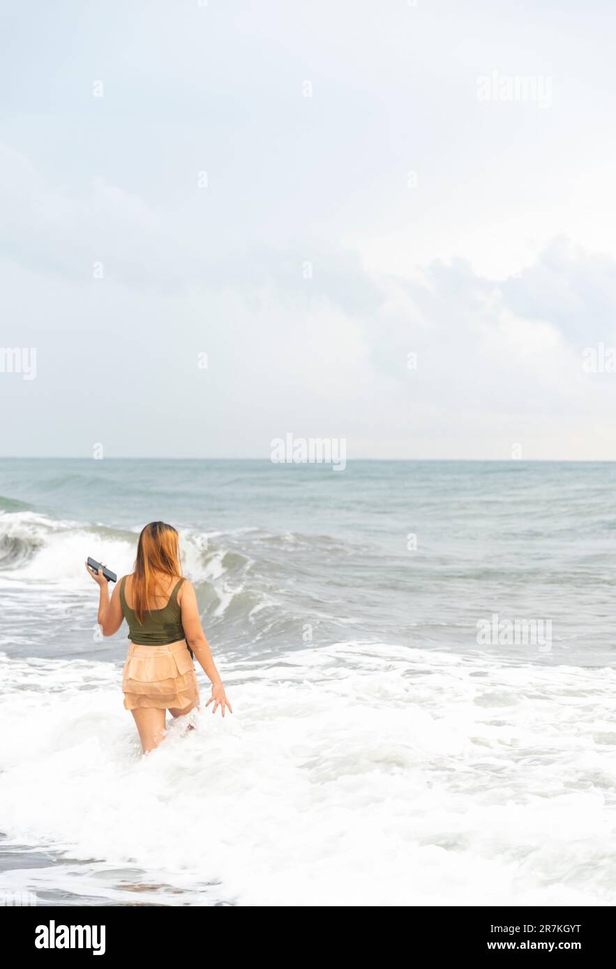 Holding Her Phone For Selfieson A Beach Near Manila At Duskaimlessly