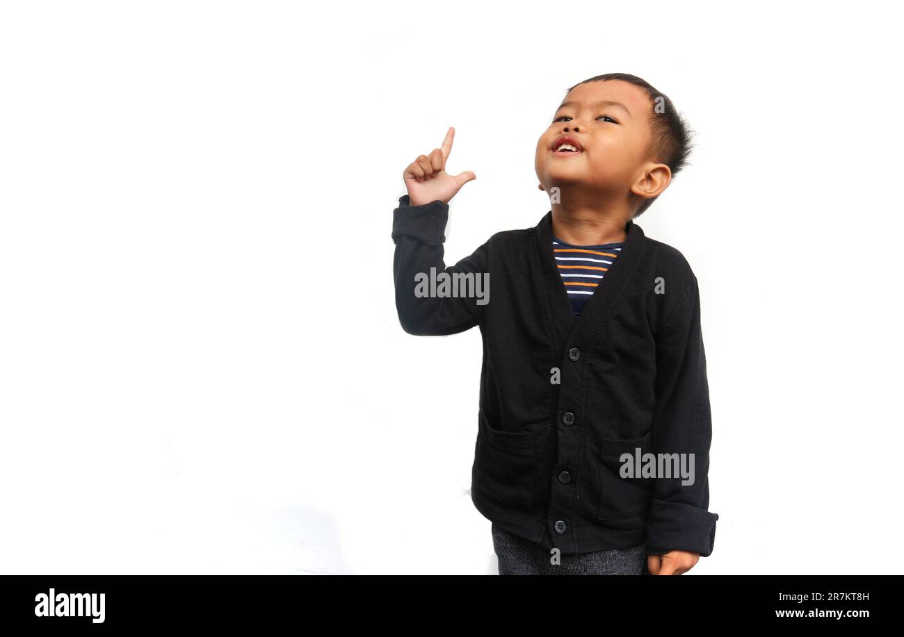 A smiling toddler boy looking and raising his hands pointing up ...
