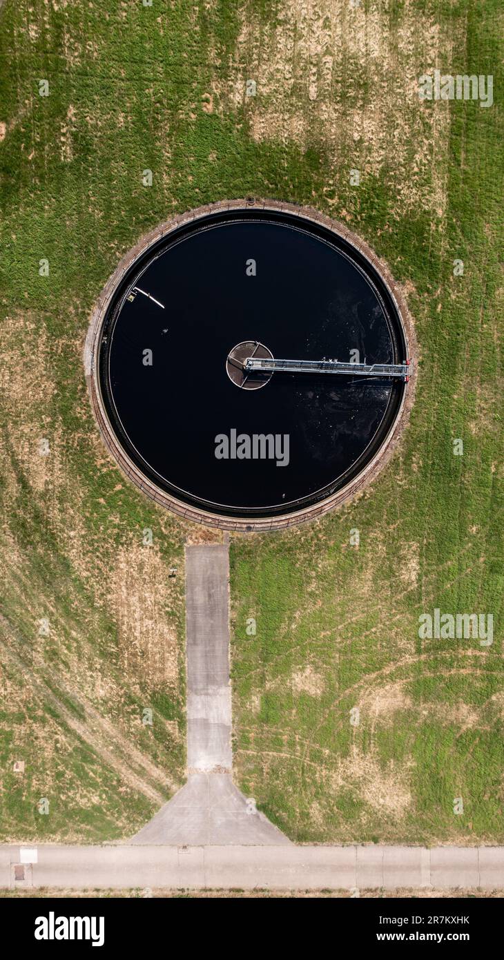 An aerial view directly above a waste water treatment works with circular storage tanks ...