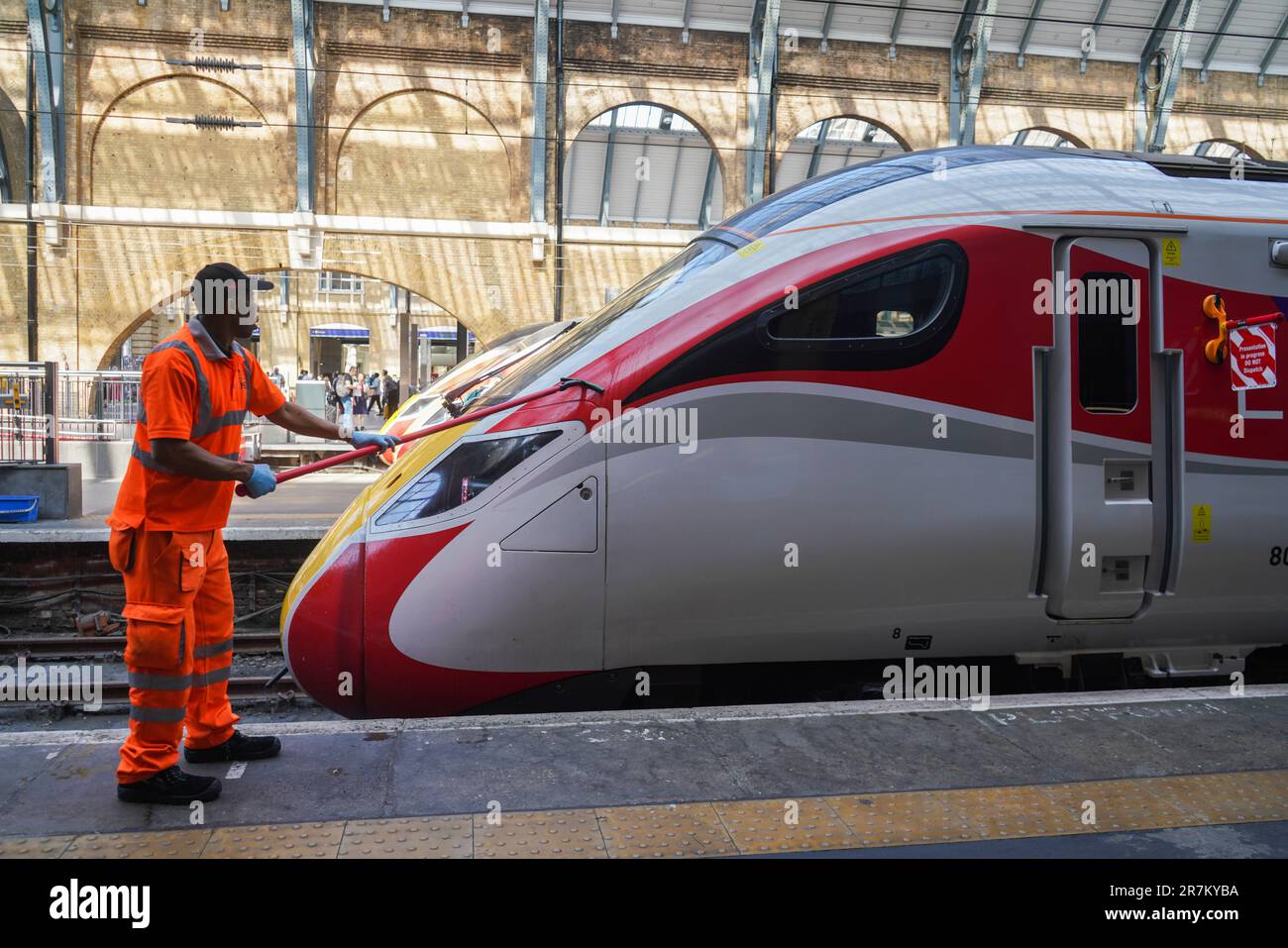London UK. 16 June 2023 . A staff member at King's Cross station cleans ...