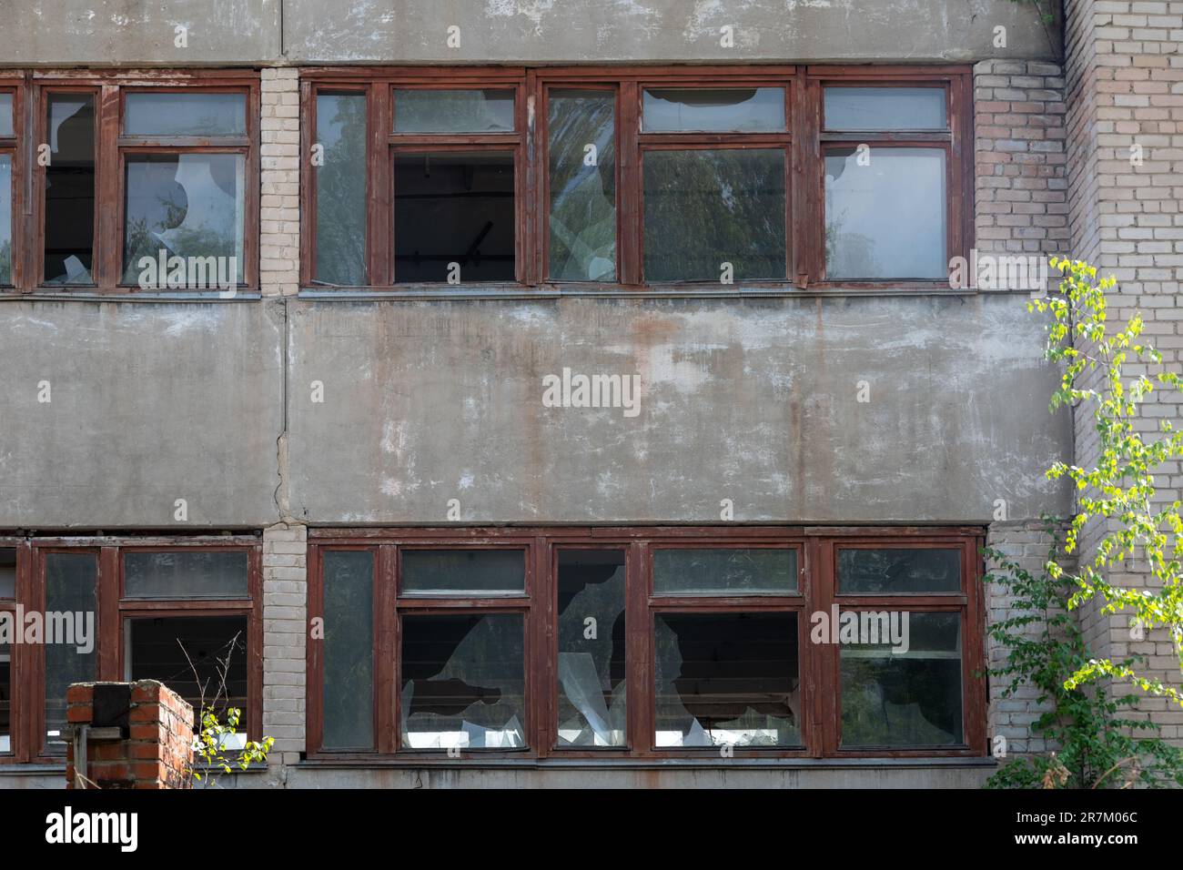 Broken windows in the facade of an old brick building. Broken glass, a hole in the glass of an ...