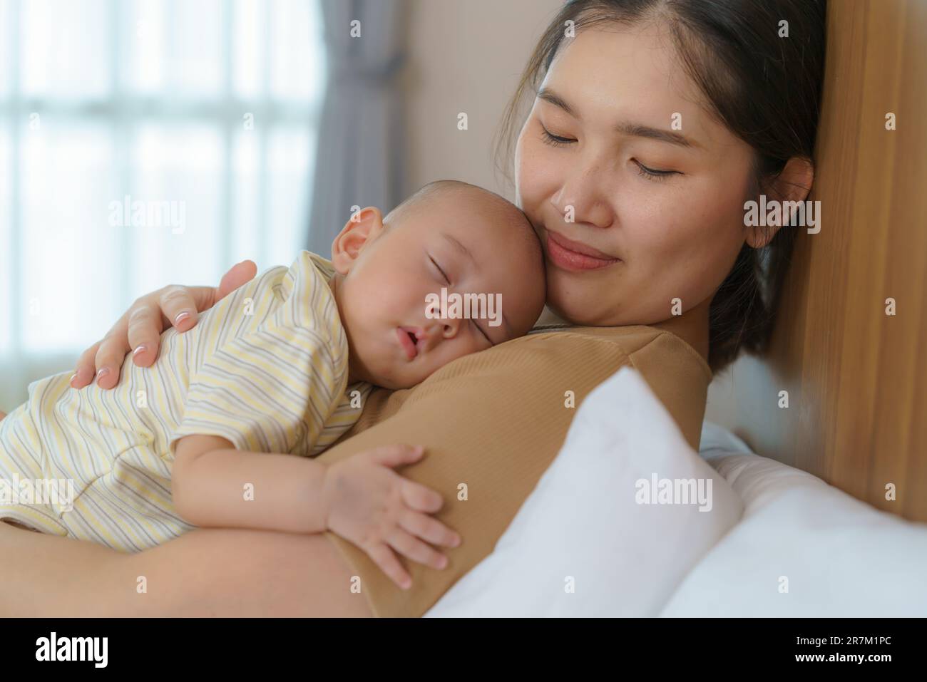 The Asian mother hug her young son so that she could have a good sleep ...