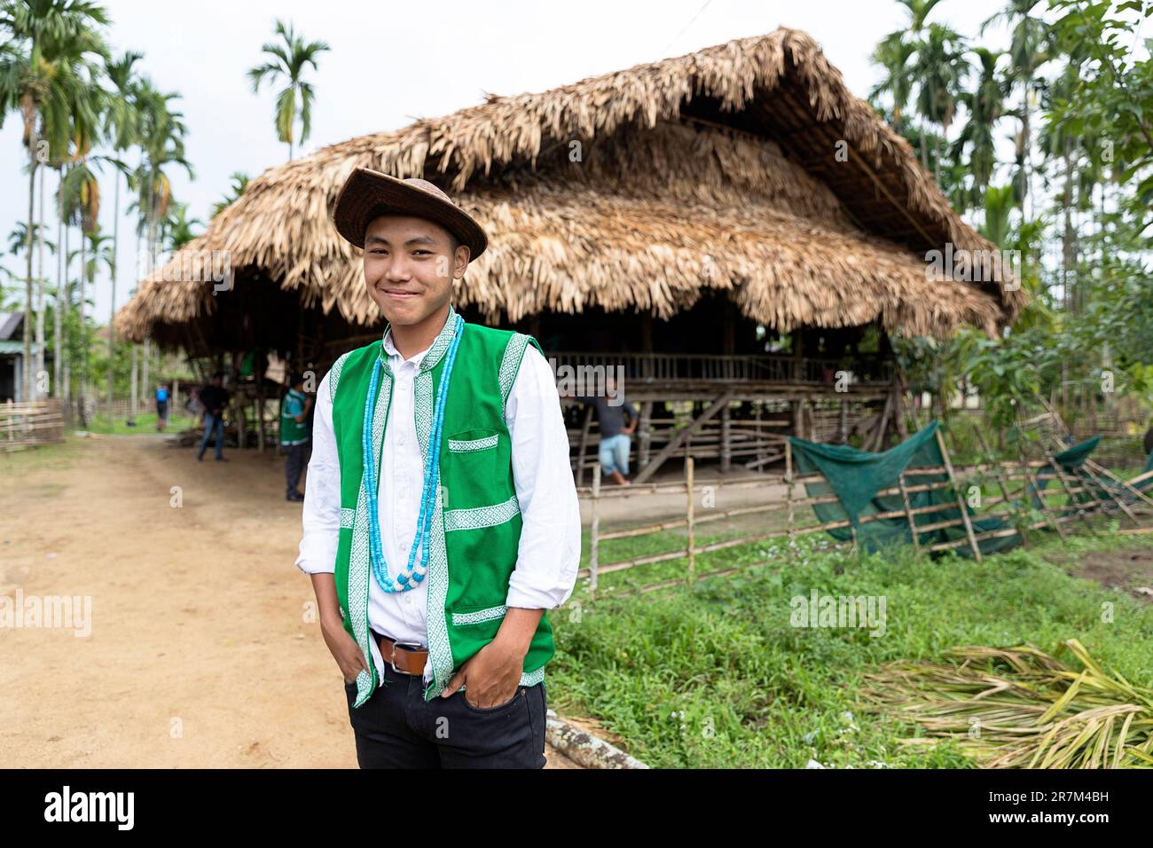 Teenager from galo tribe in traditional clothes with traditional hat on his head posing infront ...