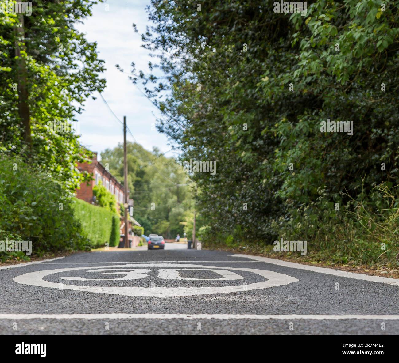 Low view of a 30 mph sign painted on the road on the approach to a ...