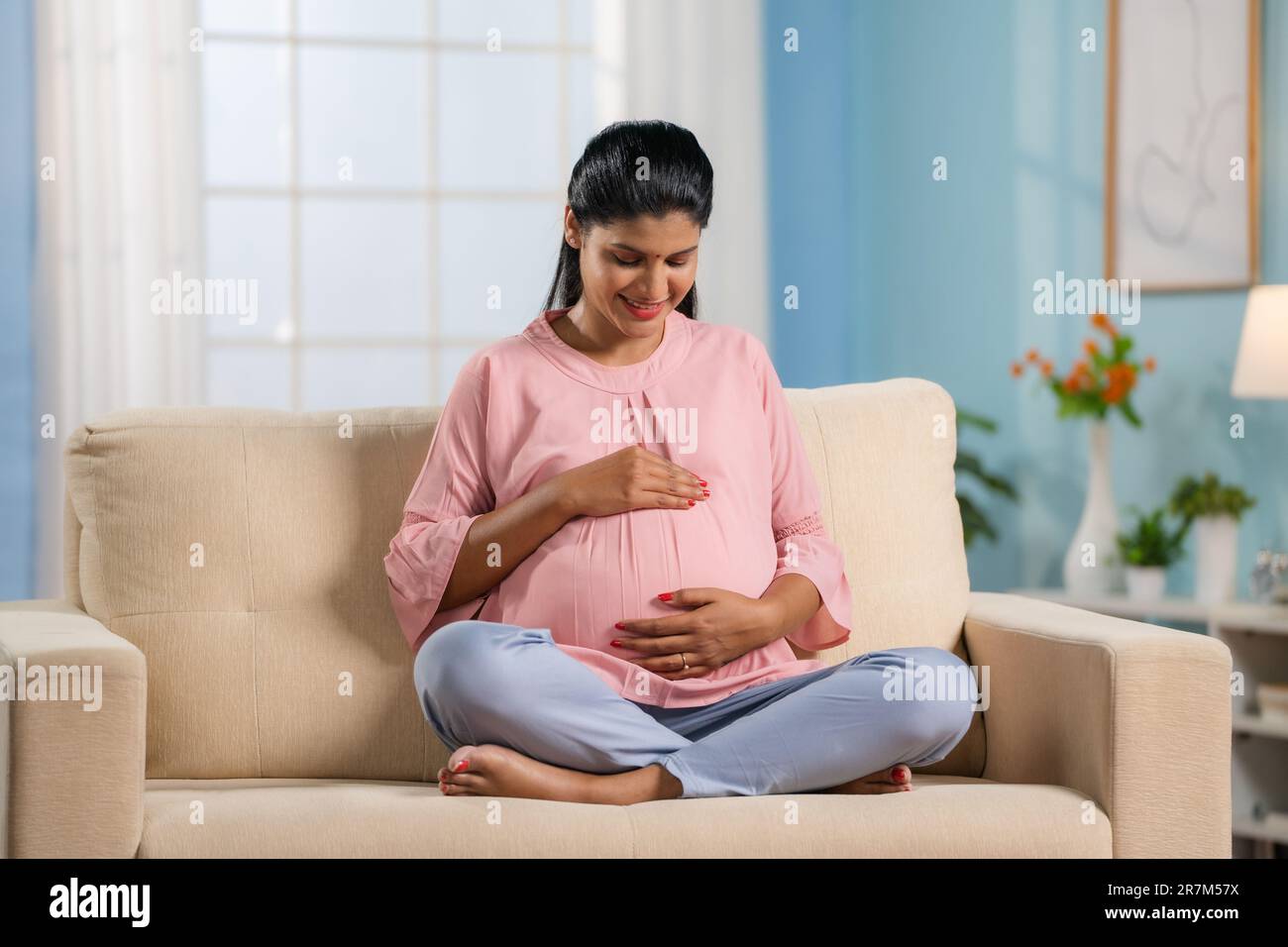 Happy indian pregnant woman feeling baby by looking and holding her ...