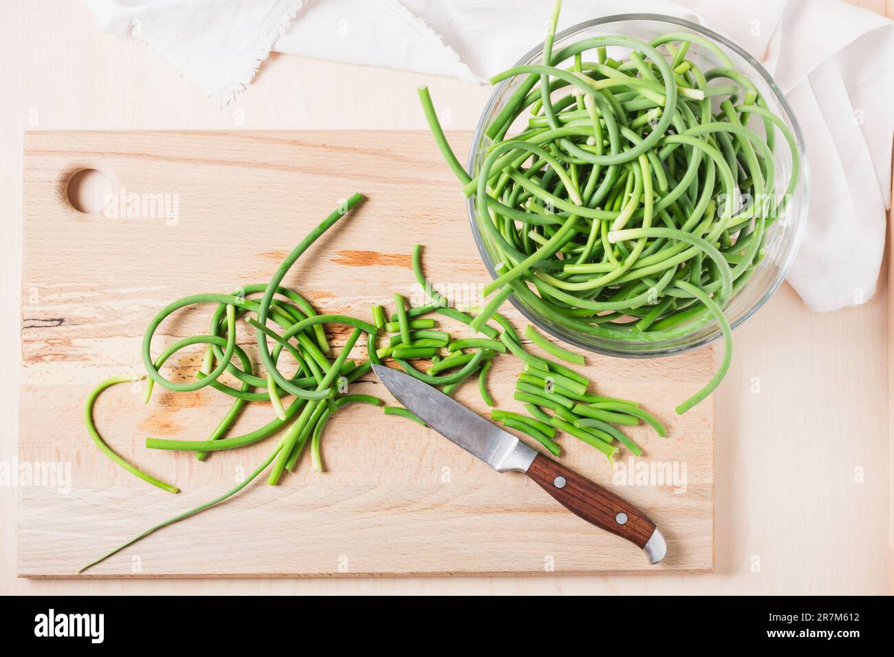 Green garlic scapes on a cutting board, top view Stock Photo - Alamy
